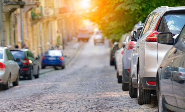 City traffic with cars parked in line on street side Stock Photo by bilanol