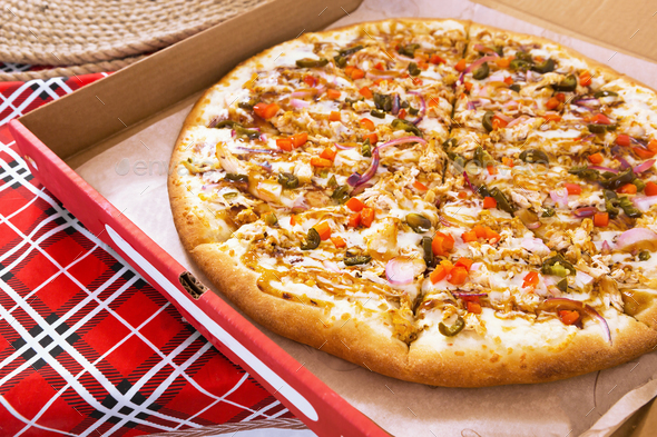 Pizza in a cardboard delivery box on a red checkered tablecloth. Fast ...