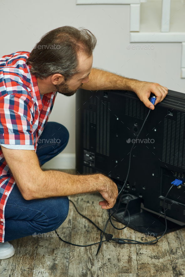 Installation process. Handyman looking focused, holding tv cable while ...