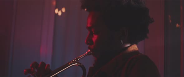 Professional musician playing the trumpet in a room with red and blue ...