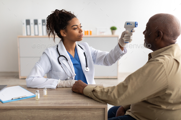 Doctor checking temperature of old man using infrared thermometer Stock ...