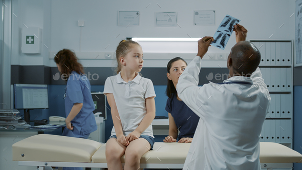Pediatrician analyzing radiography scan results with child and mother ...