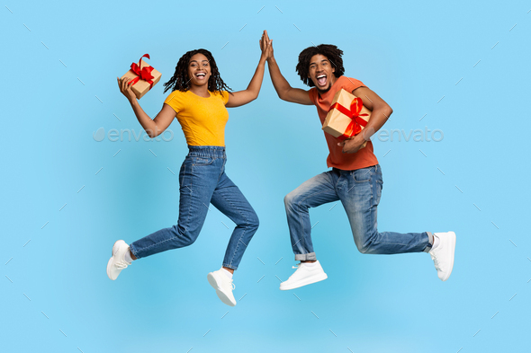 Positive black man and woman with presents giving high five Stock Photo ...