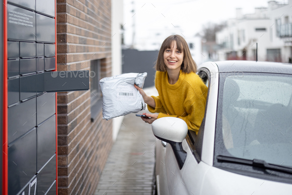 Woman getting parcel from the post office terminal right out of the car ...