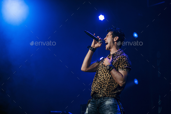 Singing artist performing before the audience at a live concert. Stock ...