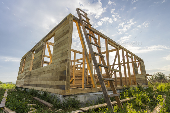 Unfinished ecological house under construction in green field on blue ...