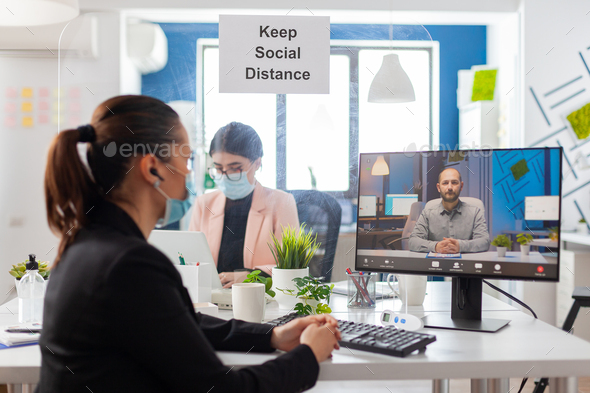 Coworkers discussing project during remote call in new normal workplace ...