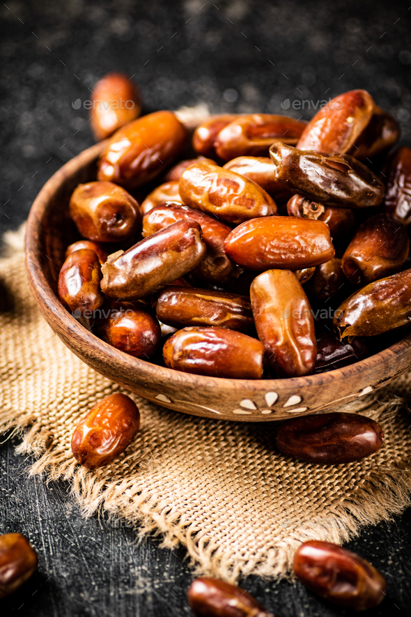 Full wooden plate with dates on the table. Stock Photo by Artem_ka2
