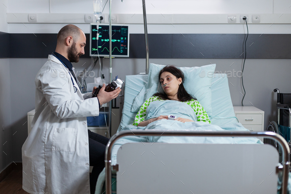 Doctor presenting medication bottles for treatment after surgery to ...