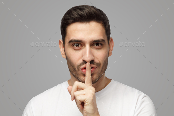 Handsome tricky man with shh gesture, asking for silence or to be quiet ...