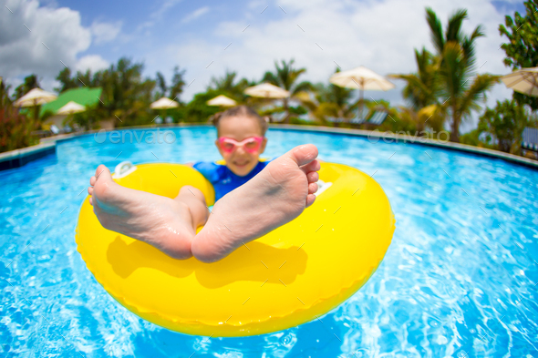 Happy little girl with inflatable rubber circle having fun in swimming ...