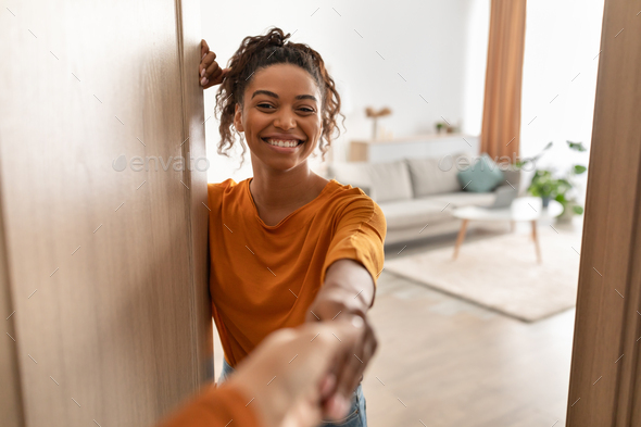 Cheerful African Woman Shaking Hands In Opened Door At Home Stock Photo ...