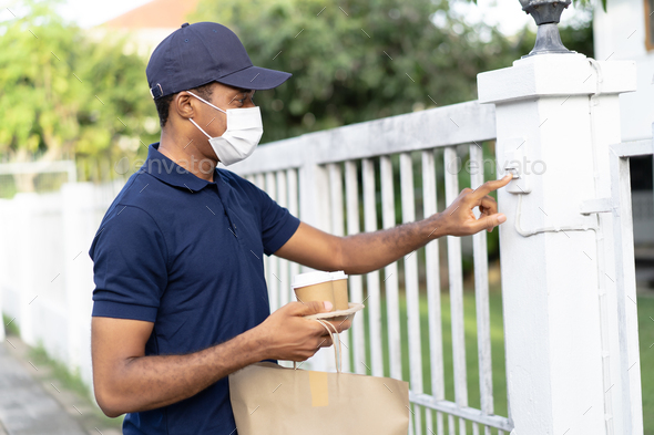 African courier guy wearing protective mask delivering to customer home ...
