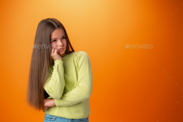 Portrait of cute thoughtful teen girl against orange background Stock ...