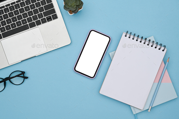 Top view smart phone, notepad, computer laptop and glasses on blue ...