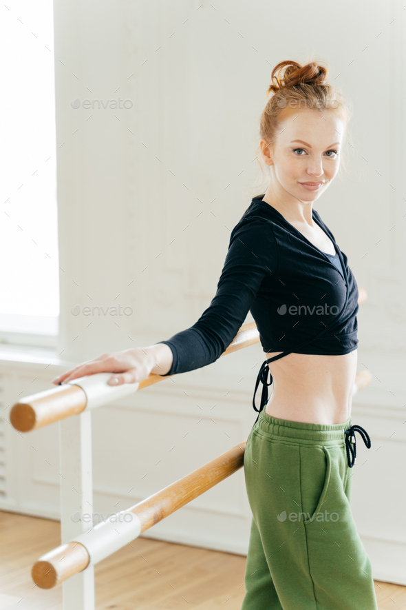 Slim young female dancer stands back to barres, demonstrates dancing ...