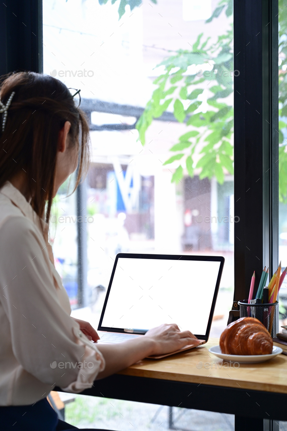 Back view young female sitting in cafe and working online with laptop ...