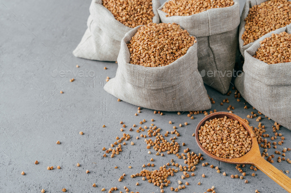 Buckwheat in small linen bags. Wooden spoon filled with protein product ...
