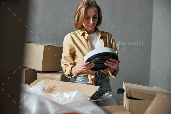 Smiling lady staring at a wall clock in her hands Stock Photo by svitlanah
