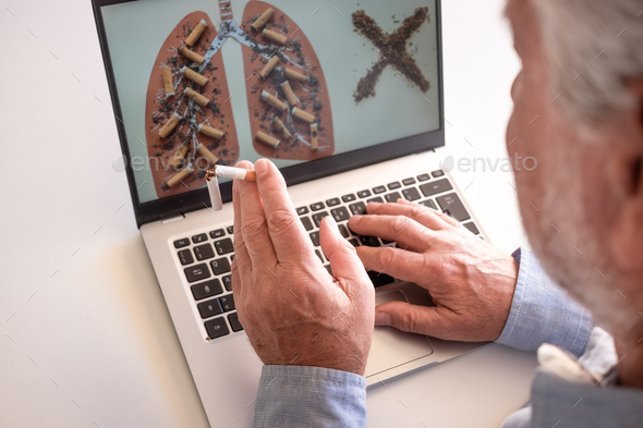 Adult hand holding a broken cigarette over laptop keyboard, ready stop ...