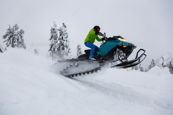 Adventurous Man Riding a Snowmobile in white snow Stock Photo by edb3_16