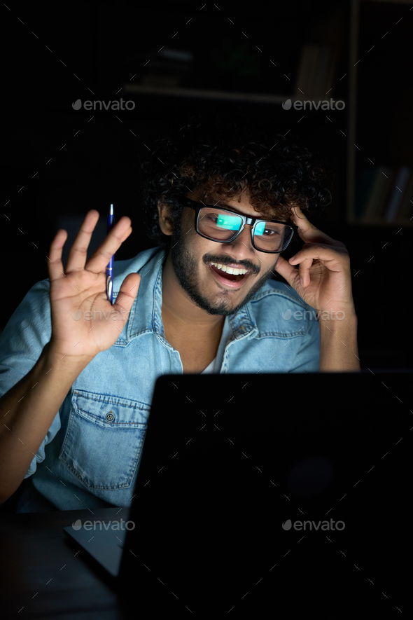 Happy young indian business man having video call meeting late at night ...