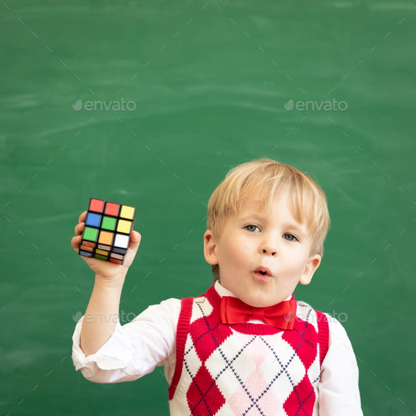 Child showing Rubik's Cube - 3D combination puzzle against green ...
