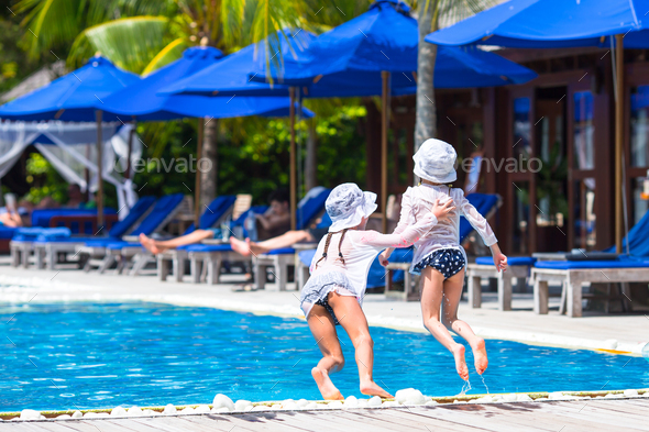 Adorable little girls having fun in outdoor swimming pool on summer ...