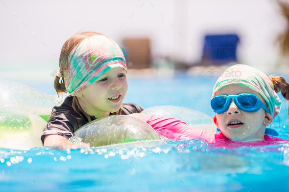 Adorable little girls relax in outdoor swimming pool on tropical ...