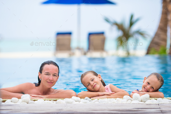 Mother and two little kids enjoying summer vacation in luxury swimming ...
