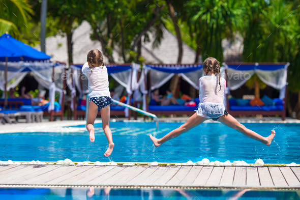 Adorable little girls having fun in outdoor swimming pool on summer ...