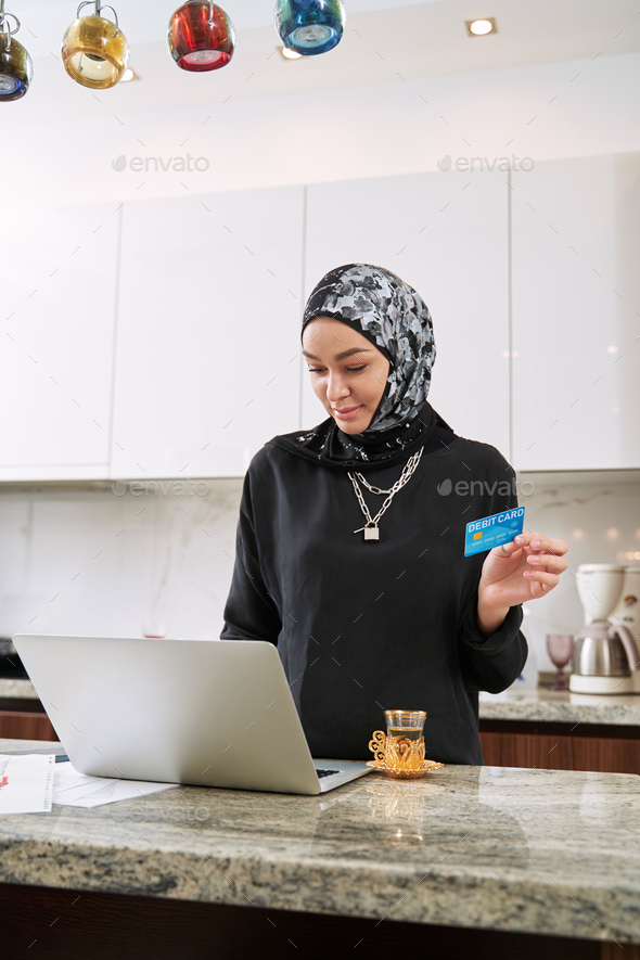 Smiling muslim female paying online purchases at home Stock Photo by ...