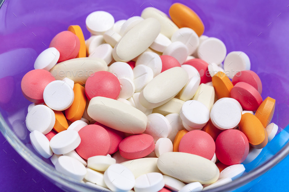 set of multi-colored tablets and capsules on a blue background Stock ...