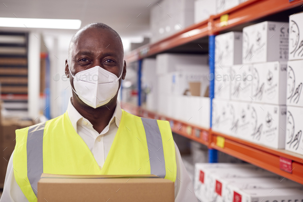 Portrait Of Male Worker Wearing PPE Face Mask Holding Box Inside ...