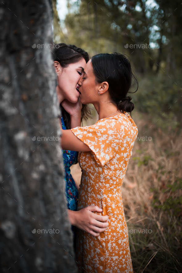 Two young lesbians kissing and caressing each other in the woods Stock Photo by ManuReyes