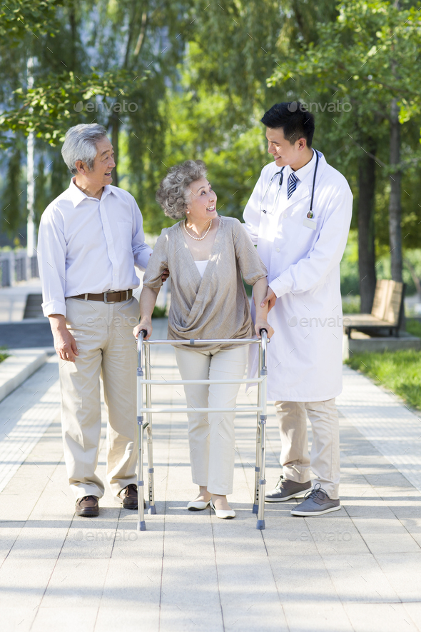 Senior woman walking with walking frame under doctor and husband's ...