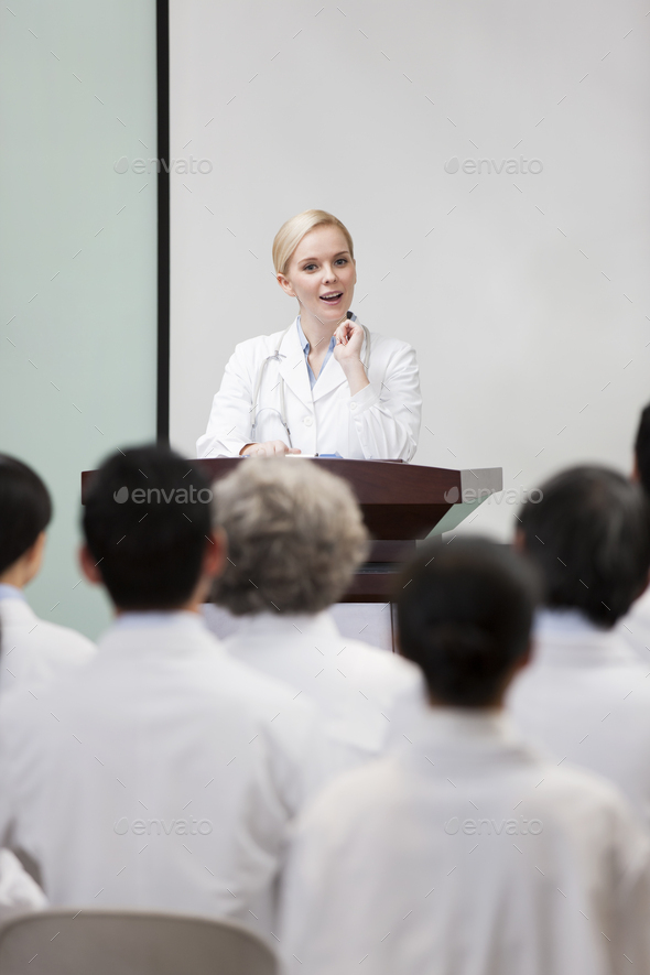 Female doctor giving speech in boardroom Stock Photo by bluejeanimages