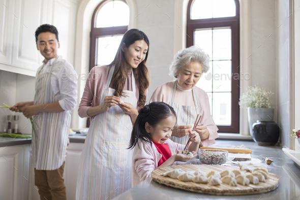 Cheerful family making dumplings in kitchen Stock Photo by bluejeanimages