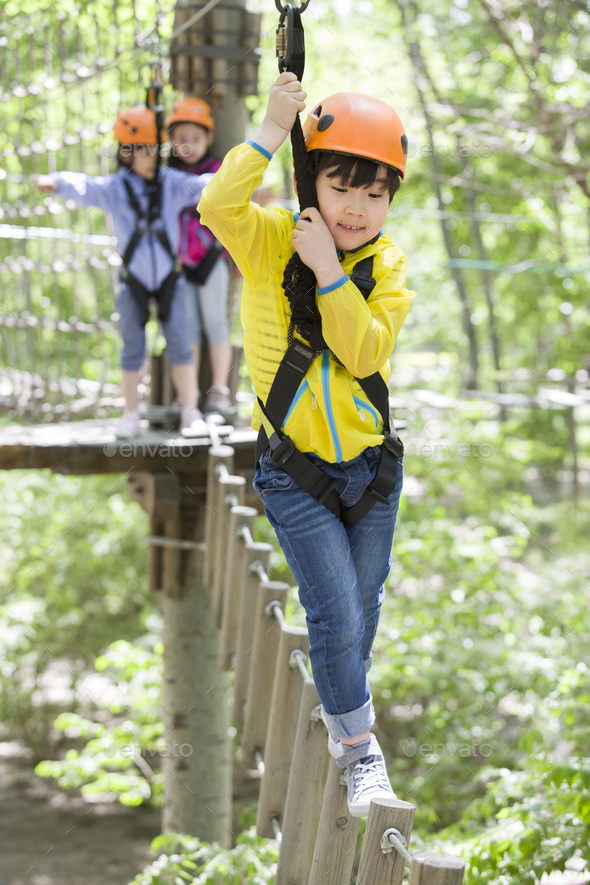 Happy children playing in tree top adventure park Stock Photo by ...