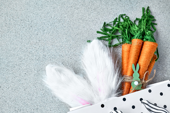 Bunny rabbit ears and craft wool thread carrots in white paper bag on ...
