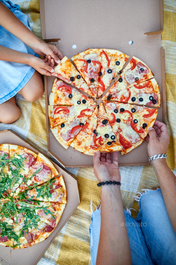Sharing pizza, hands taking a piece of pizza from a box outdoor, Stock ...
