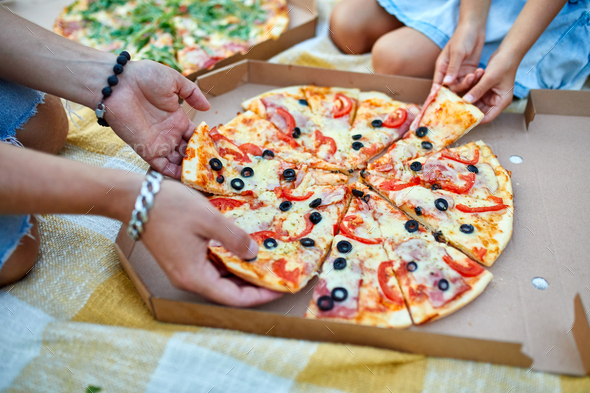 Sharing pizza, hands taking a piece of pizza from a box outdoor, Stock ...