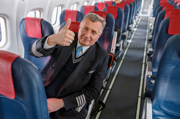 Male aircraft pilot sitting on passenger seat and giving thumbs up ...