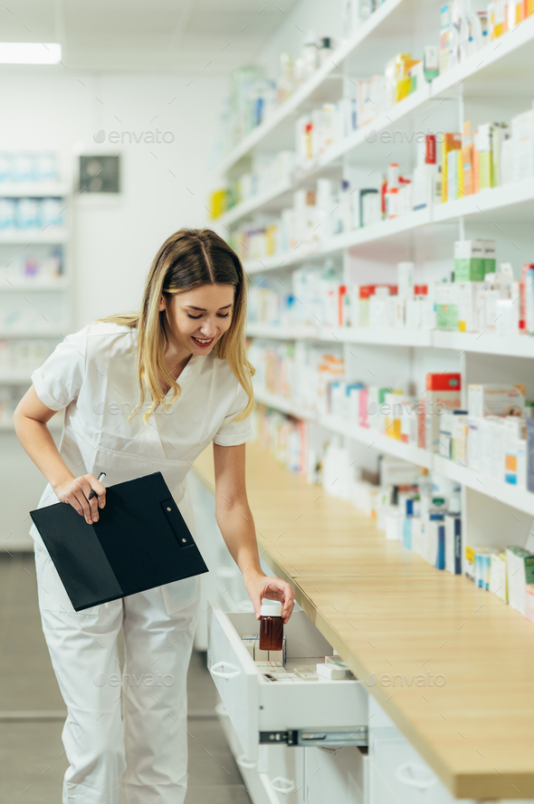 Beautiful female pharmacist working in a pharmacy while checking ...