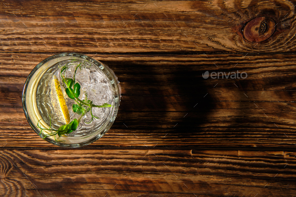 Overhead view of glass with cold water with ice and lemon casting a ...