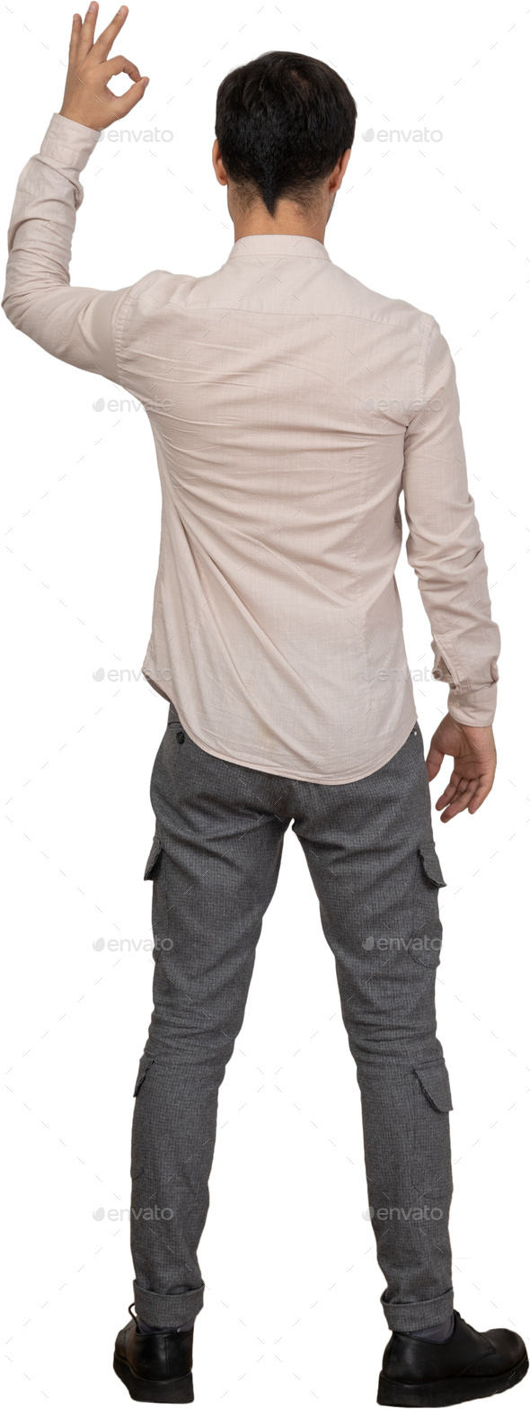 a man standing in front of a white wall with his hand up Stock Photo by ...