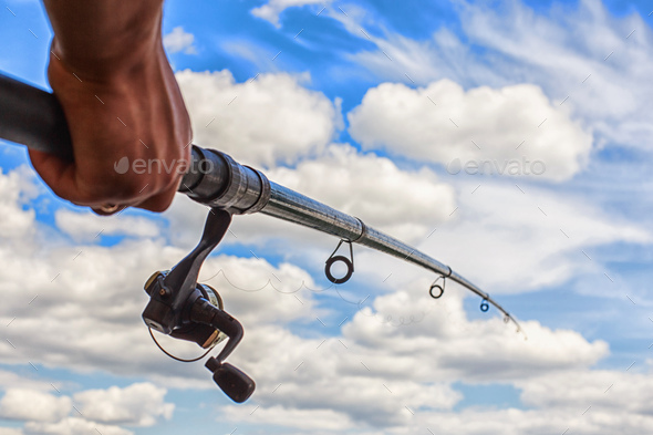 fishing rod on a blue sky background in a man's hand Stock Photo by ...