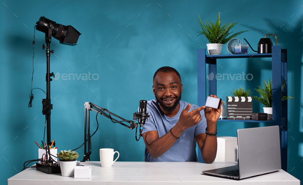 Vlog reviewer presenting small video light sitting at desk with laptop ...