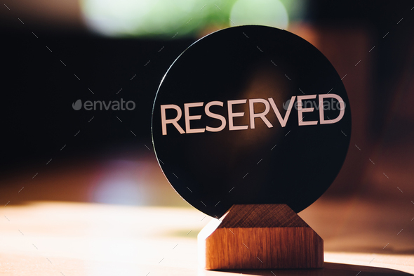 Wooden reserved sign in restaurant. Table set. Capital letters ...