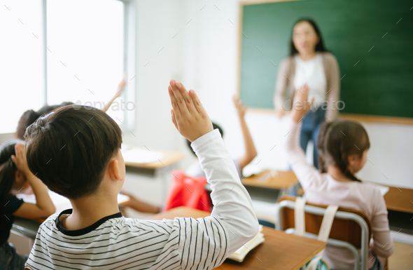 Pupils raising their hands during class at the elementary school. Stock ...